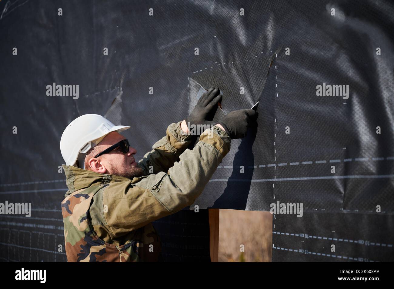 Male builder installing waterproof membrane on the wall of future ...
