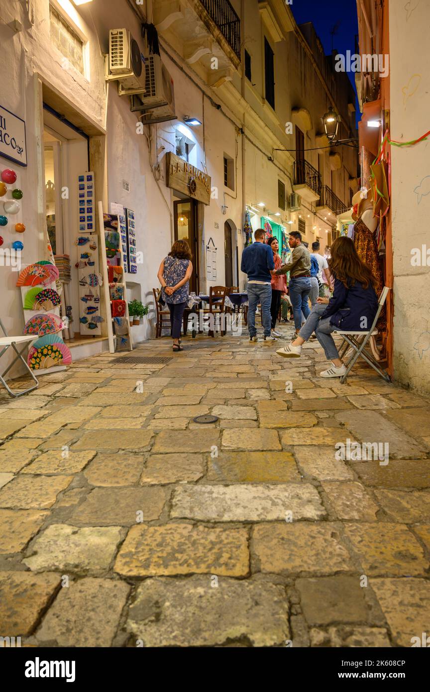 Tourists and locals walking along a typical narrow and cobbled street ...