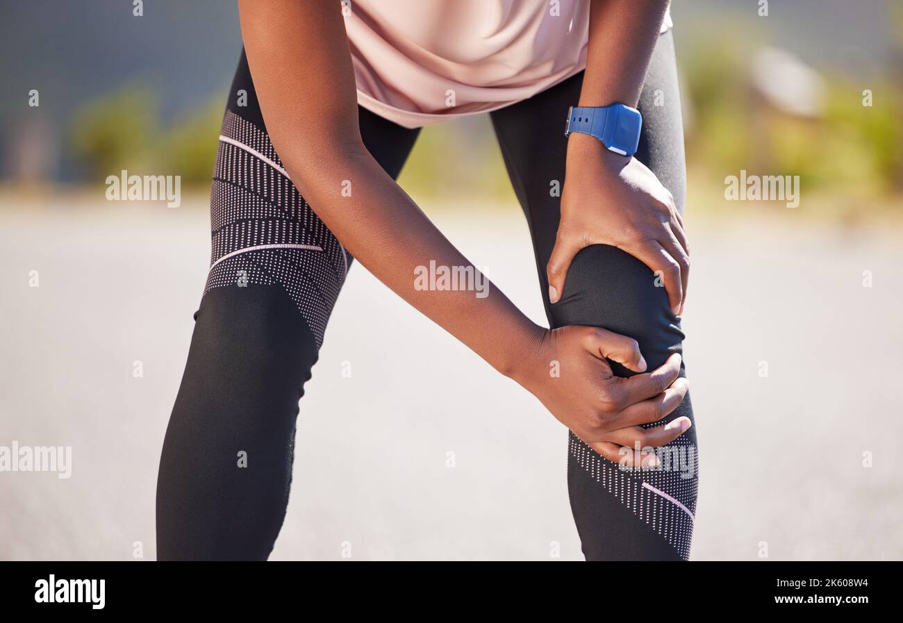Active woman holding her leg in pain while exercising outdoors. Closeup ...