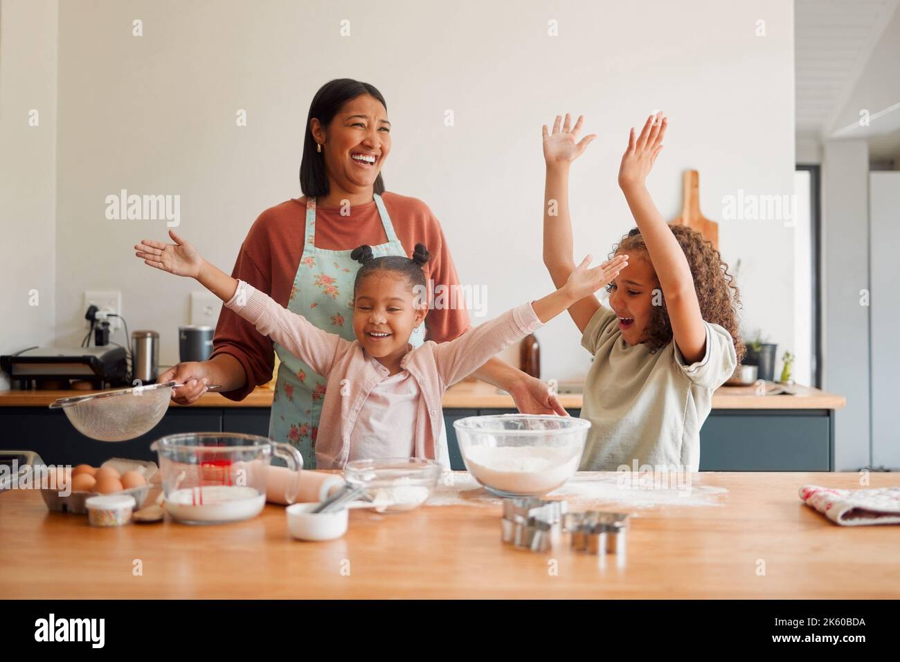 Females only, happy mixed race family of three cooking in a messy ...