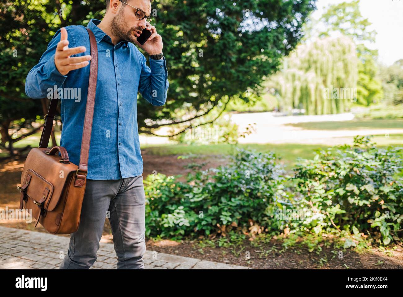 Worried young adult employee with a hand bag, having a discussion wit ...