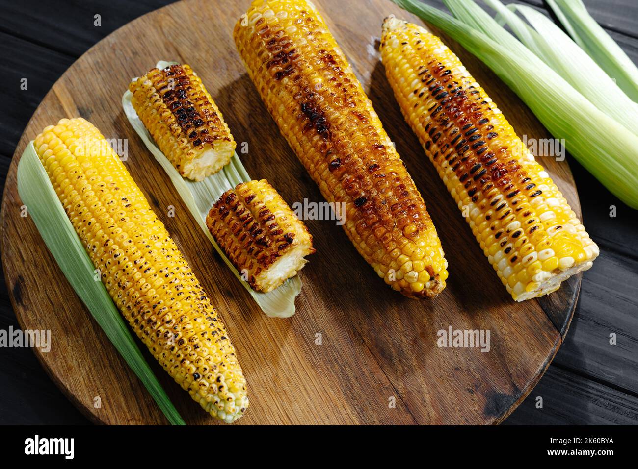 Roasted barbecue corn. Grilled corn on a dark wooden background. Slices ...