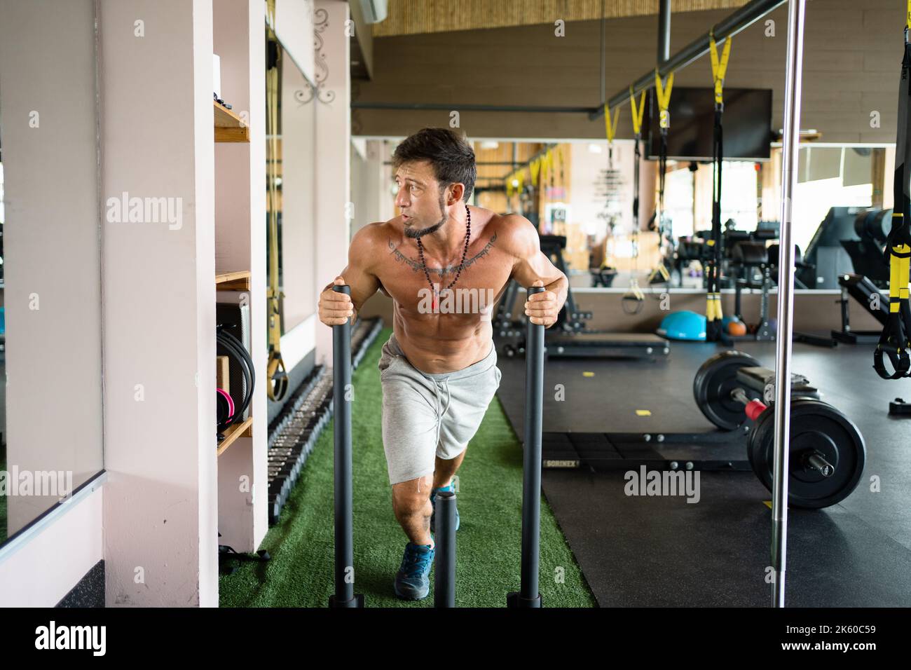Distracted strong man dragging weight inside a gym Stock Photo - Alamy