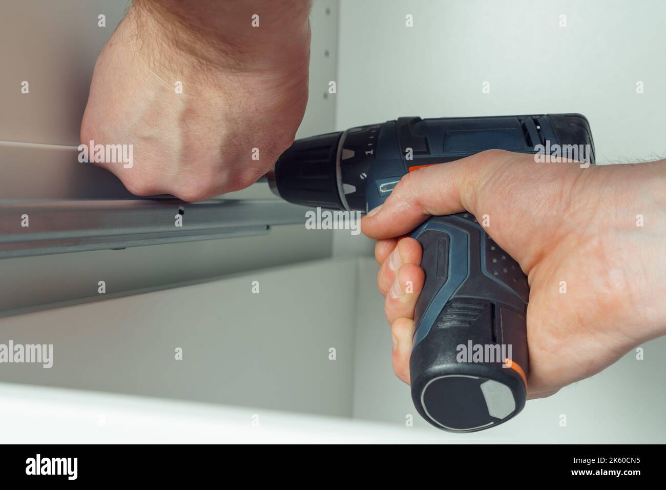 Male hands hold cordless electric screwdriver, screw to fix rail ...