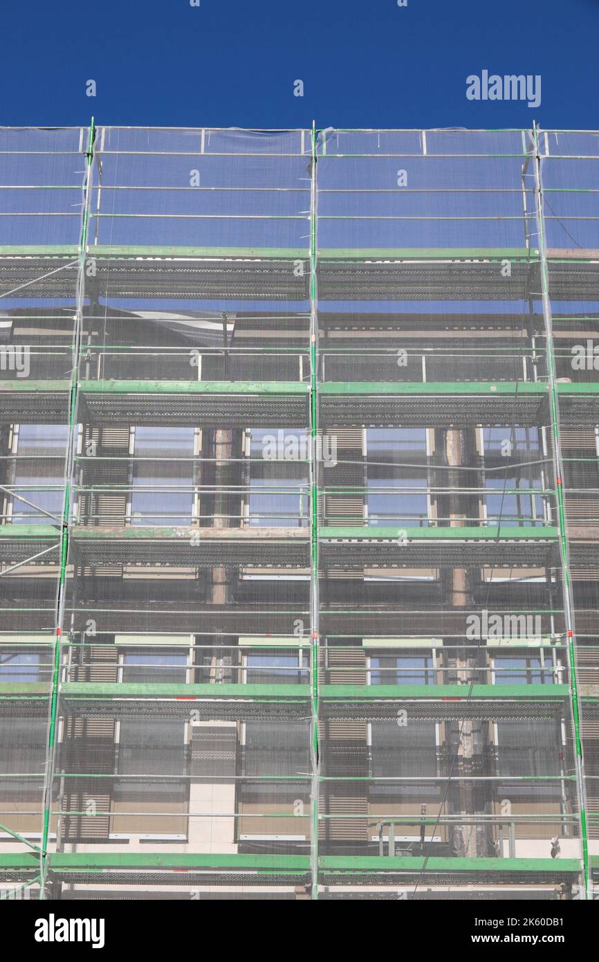 Protective netting on construction site scaffolding. Generic office ...