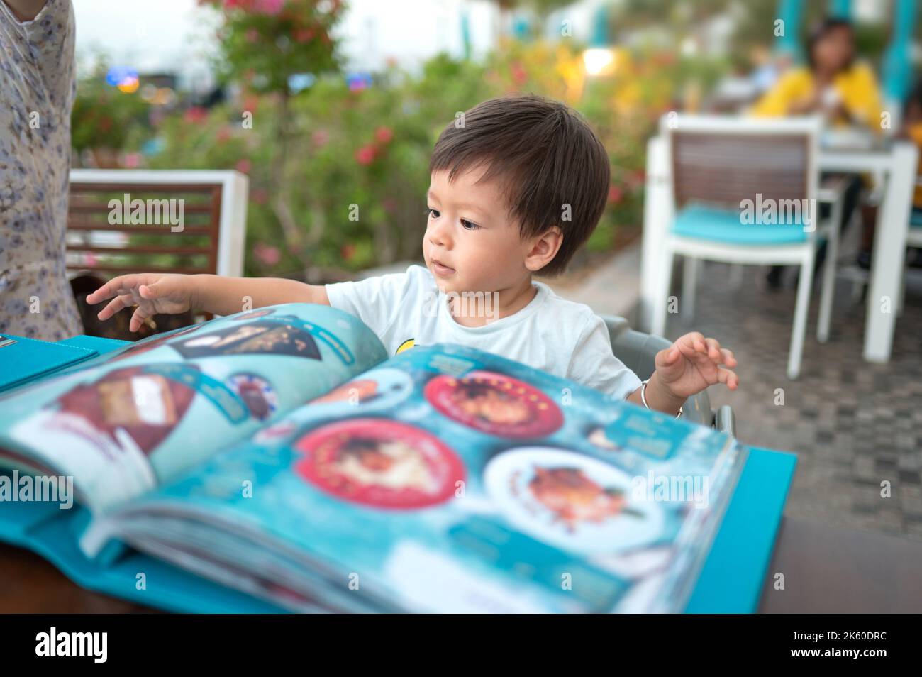 Handsome mixed race one year old baby boy looking at the menu to choose ...
