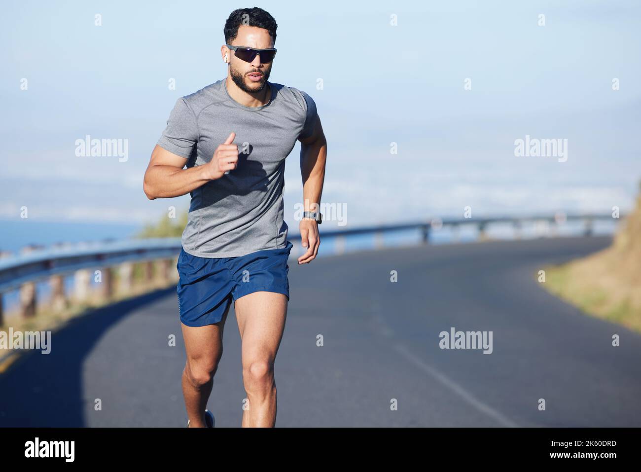 Training, exercise and man running on road in city in summer with ocean ...