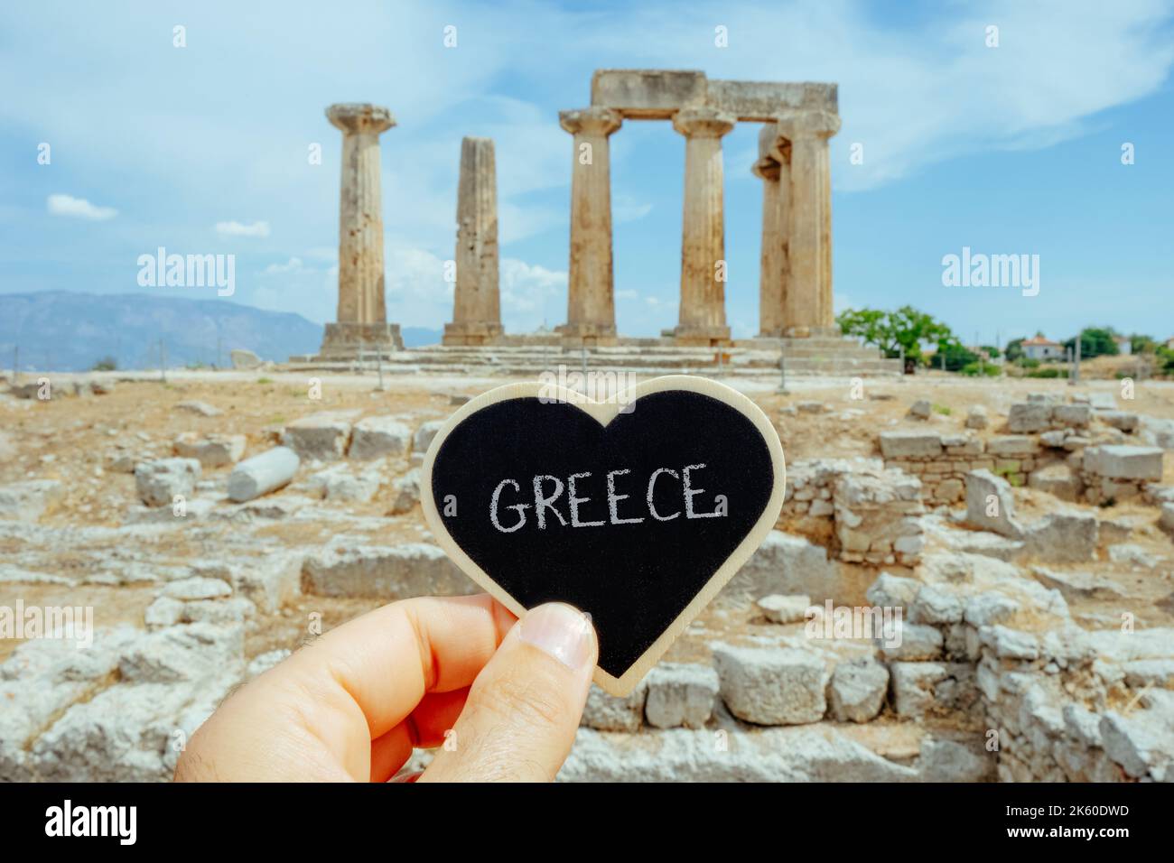 a man holds a heart-shaped sign with the word Greece written in it, in ...