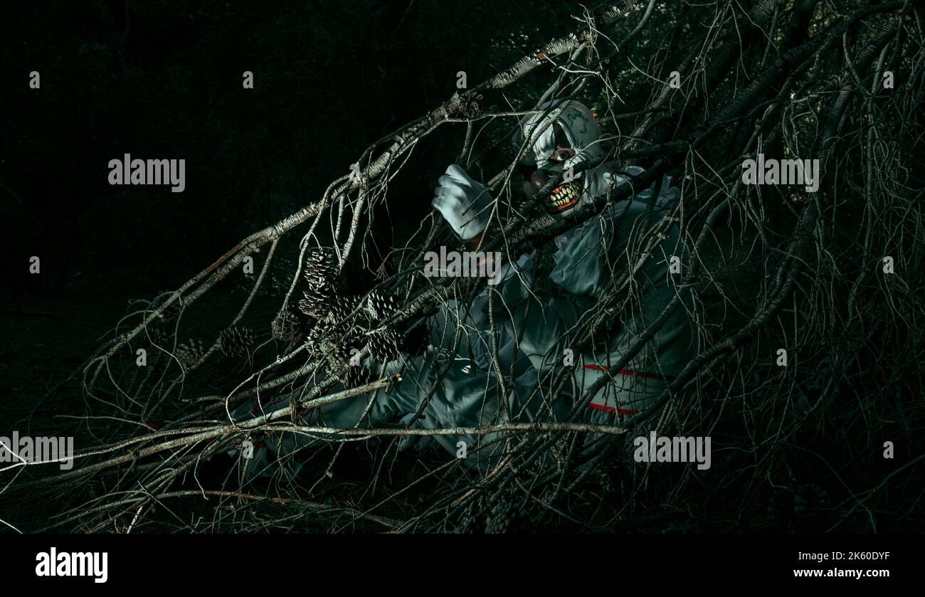 a creepy bald evil clown, wearing a gray costume with a white ruff, is ...