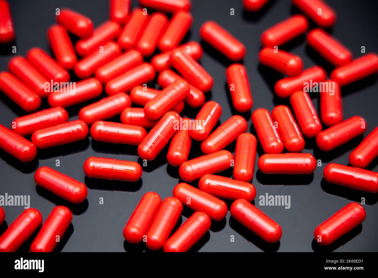A pile of red capsules on black surface Stock Photo - Alamy