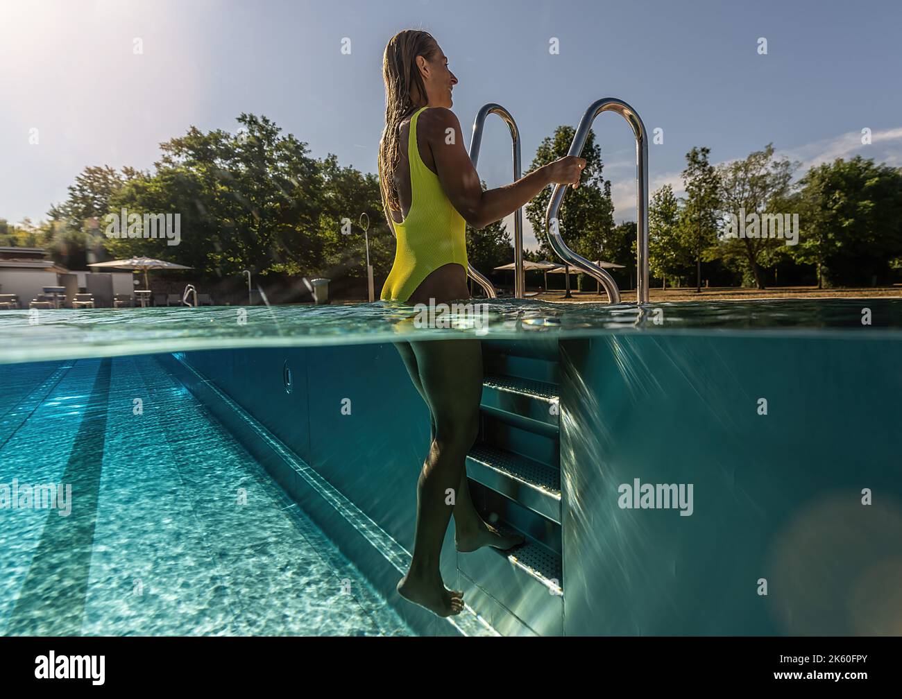 young woman stands by a ladder in a swimming pool, Split above and ...