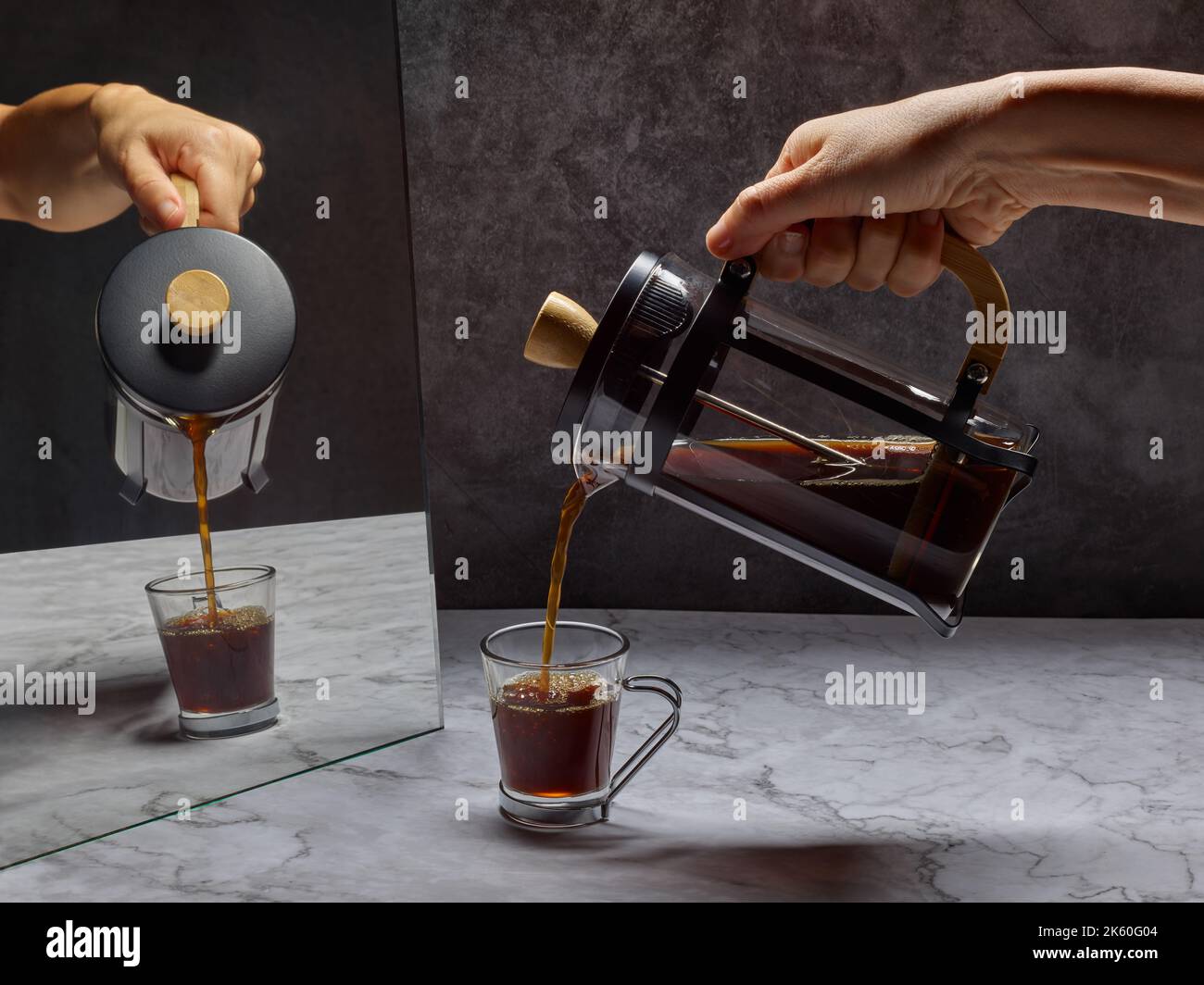 Hand with a coffee pot pouring coffee into a cup, with a mirror ...