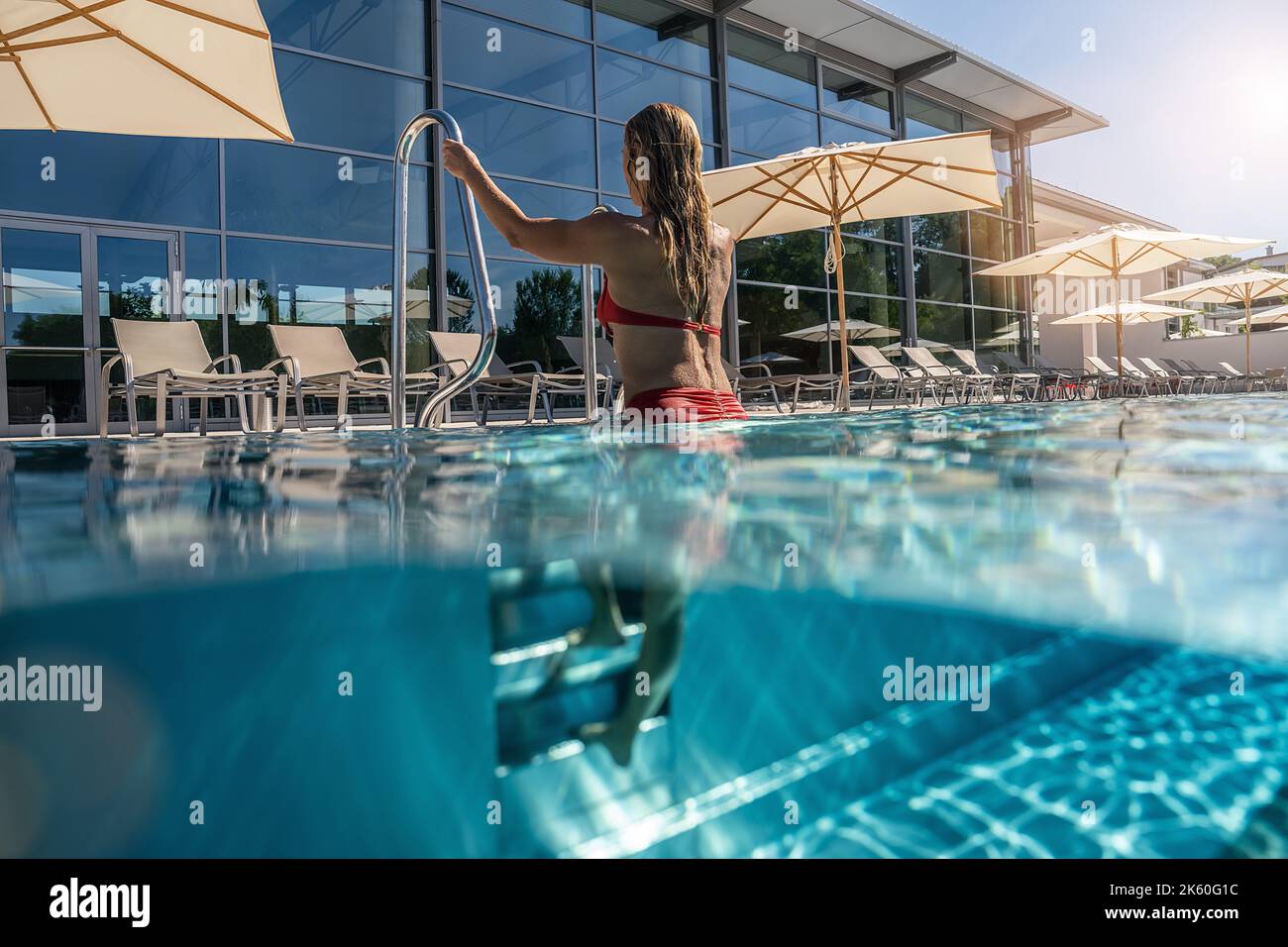 Above and underwater photo of a woman using ladder to get to swimming ...
