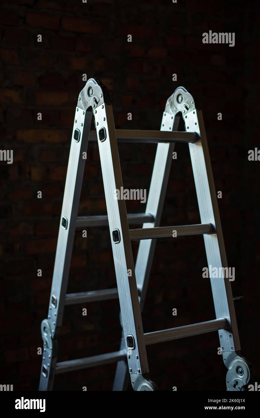 Construction. Metal folding step ladder in a dark room on a ...