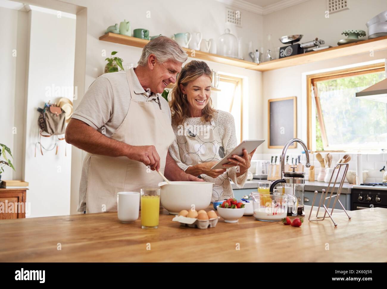 Baking, tablet and retirement with a senior couple cooking in the ...