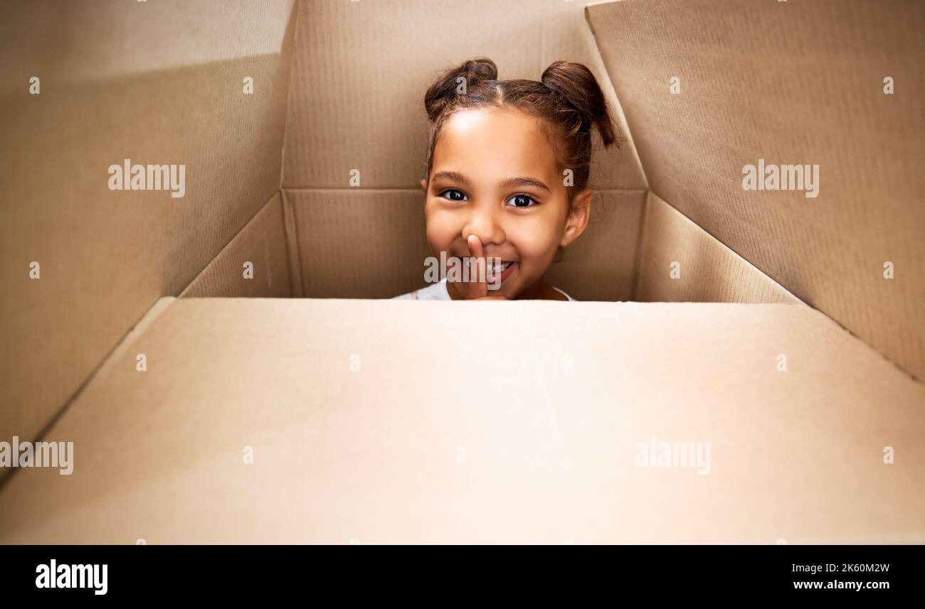 Portrait of a cute little hispanic girl playing with a cardboard box in ...