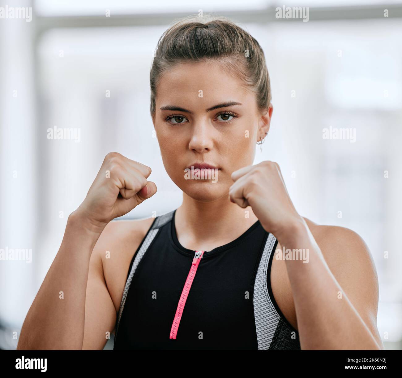 Portrait of serious trainer in boxing stance alone in gym. Focused ...