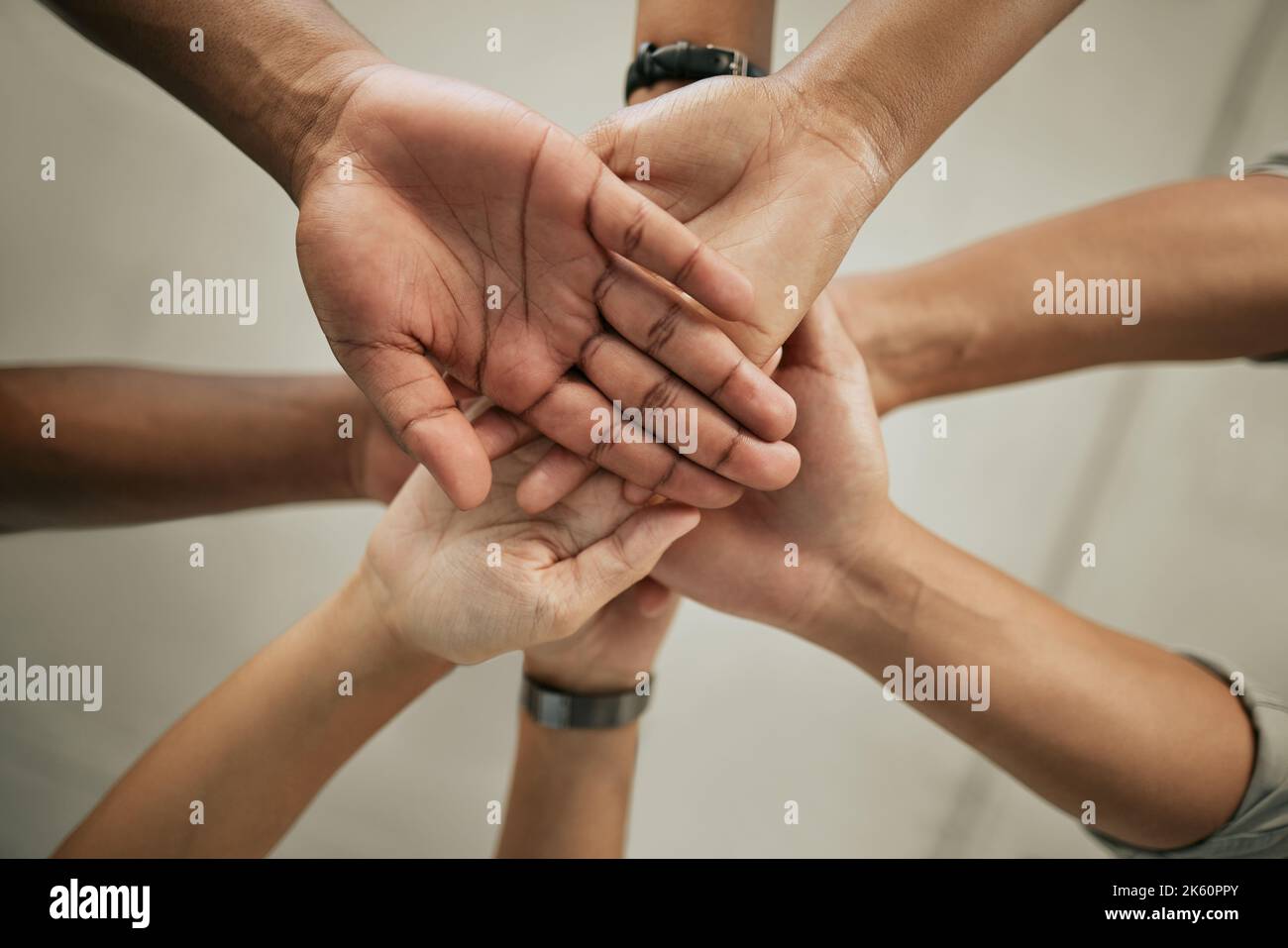 Close up of stacked hands. Group of colleagues putting hands together in the office. Creative ...