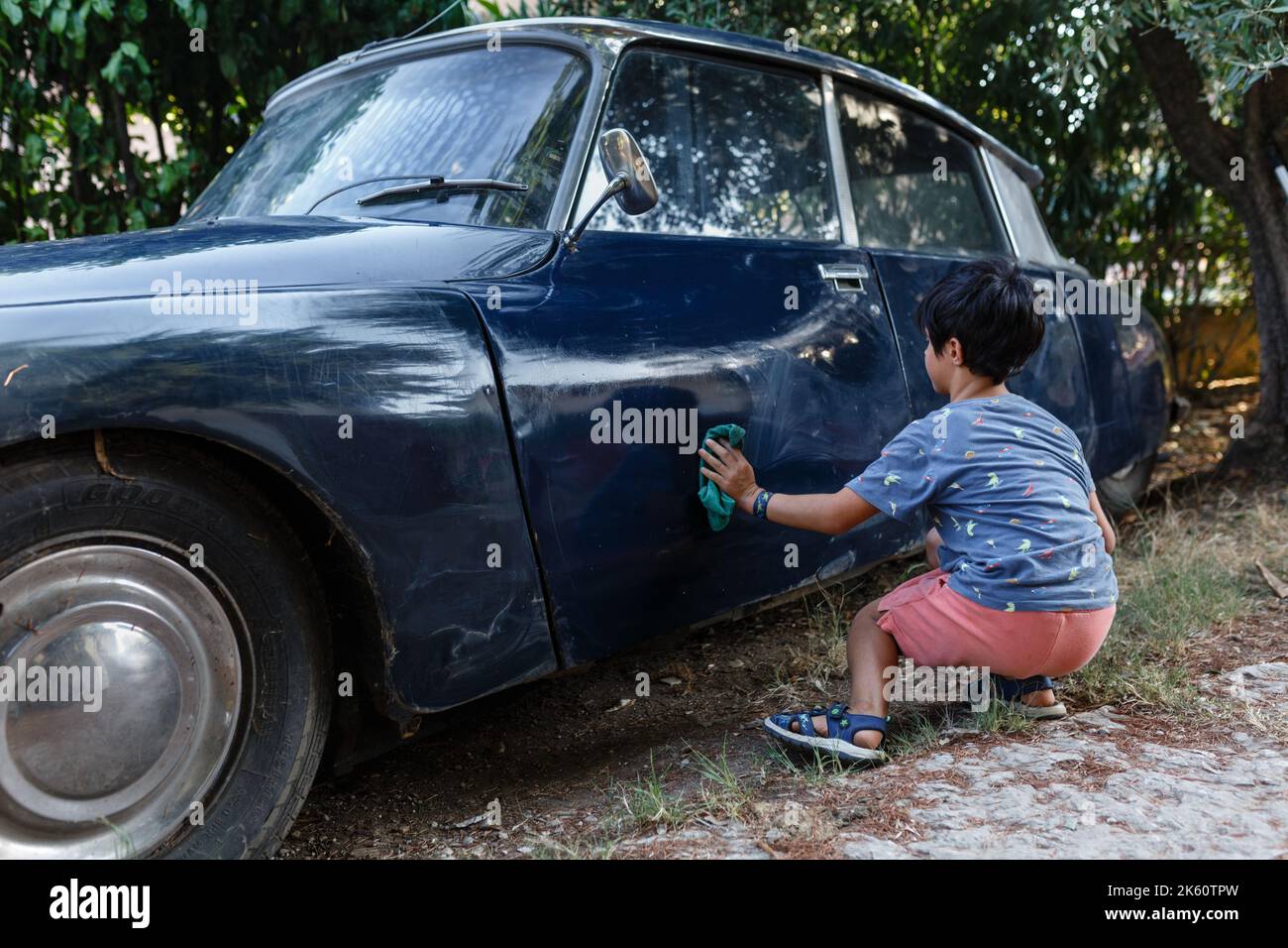 Girl with short black haircut washing blue car in the garden Stock ...