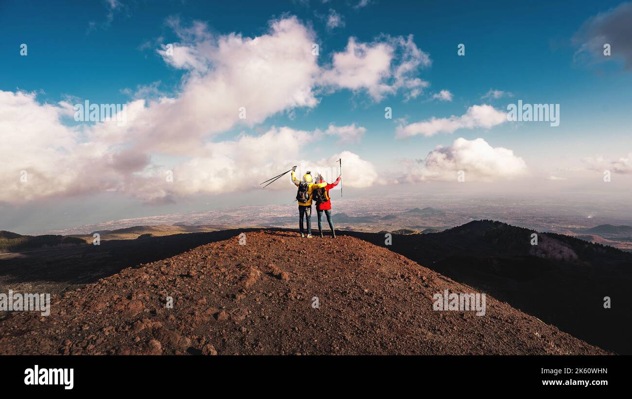 A couple of young hikers look at the lava-rocky panorama from the ...