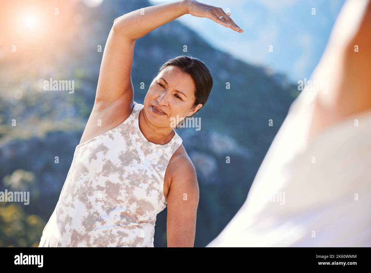 Mature woman stretching her hand over her head while exercising ...
