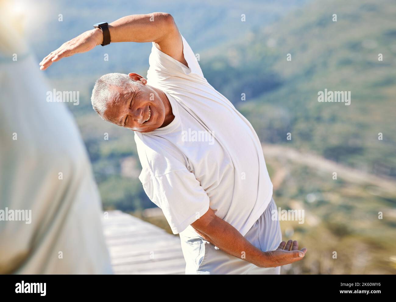 Senior man laughing while stretching his hand over his head while ...