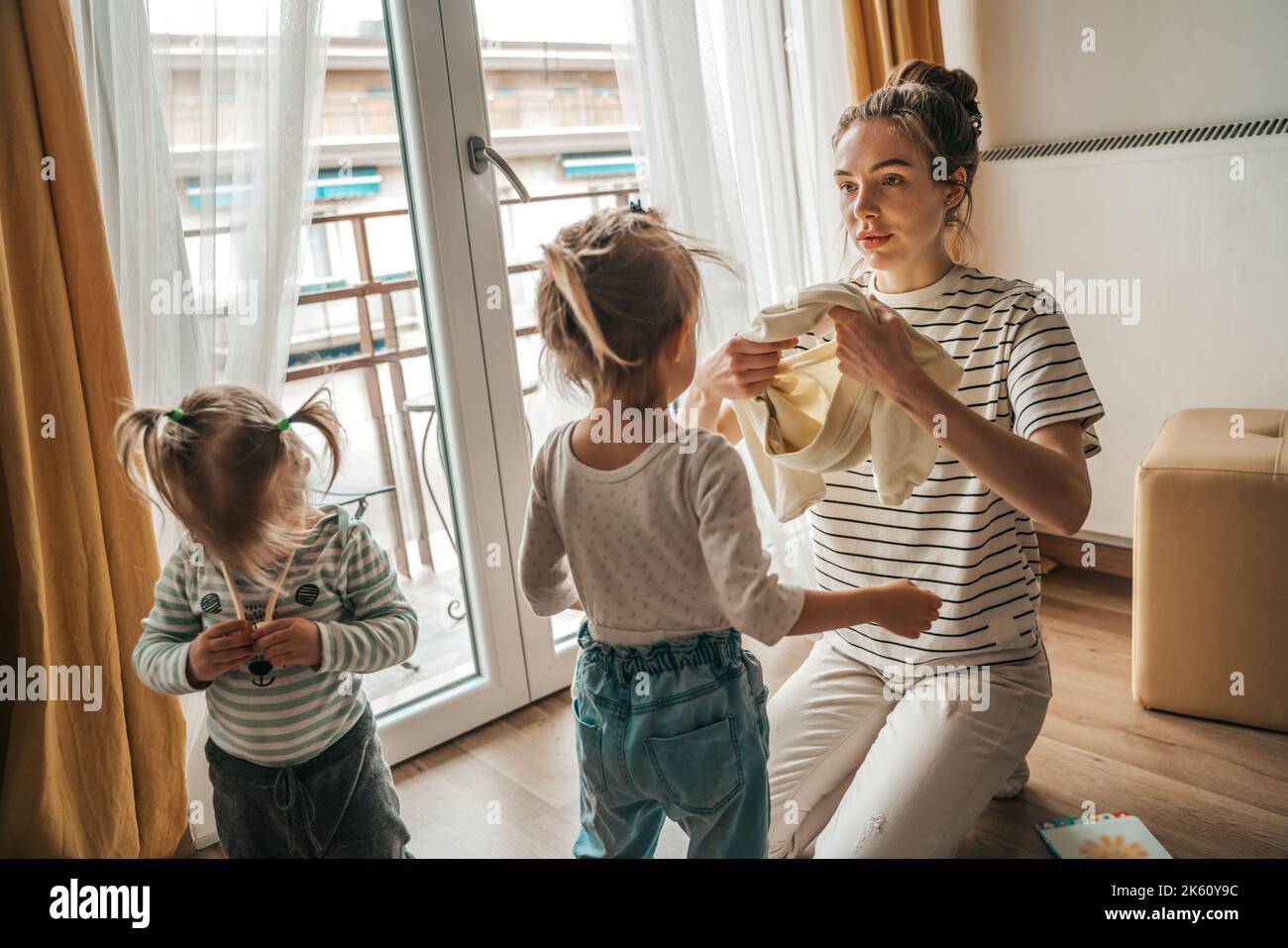 Caring female parent dressing her child by the window Stock Photo - Alamy