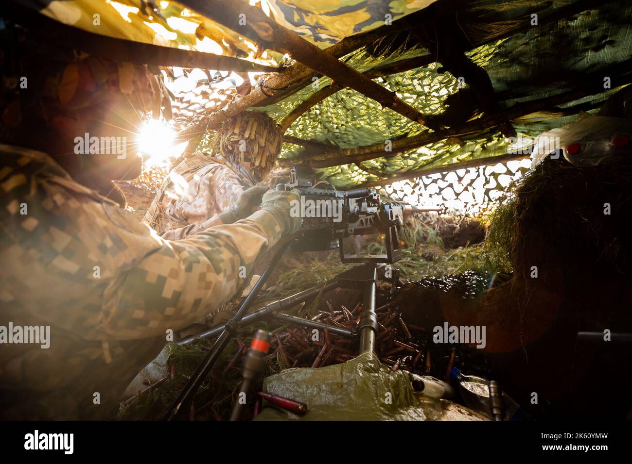 Close-up soldiers firing a 50 Cal Machine gun with spent brass around ...