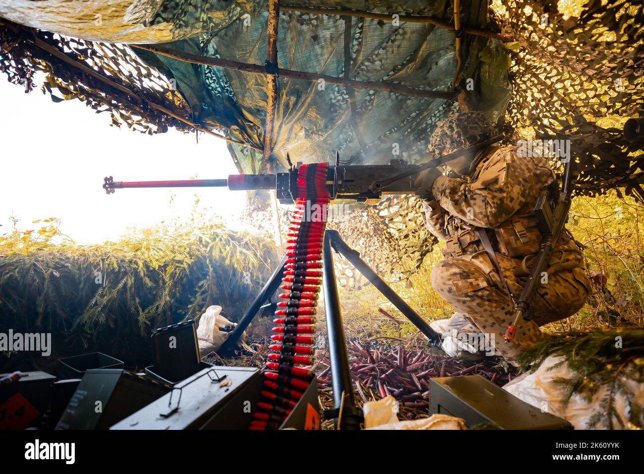 Close-up soldiers firing a 50 Cal Machine gun with spent brass around ...
