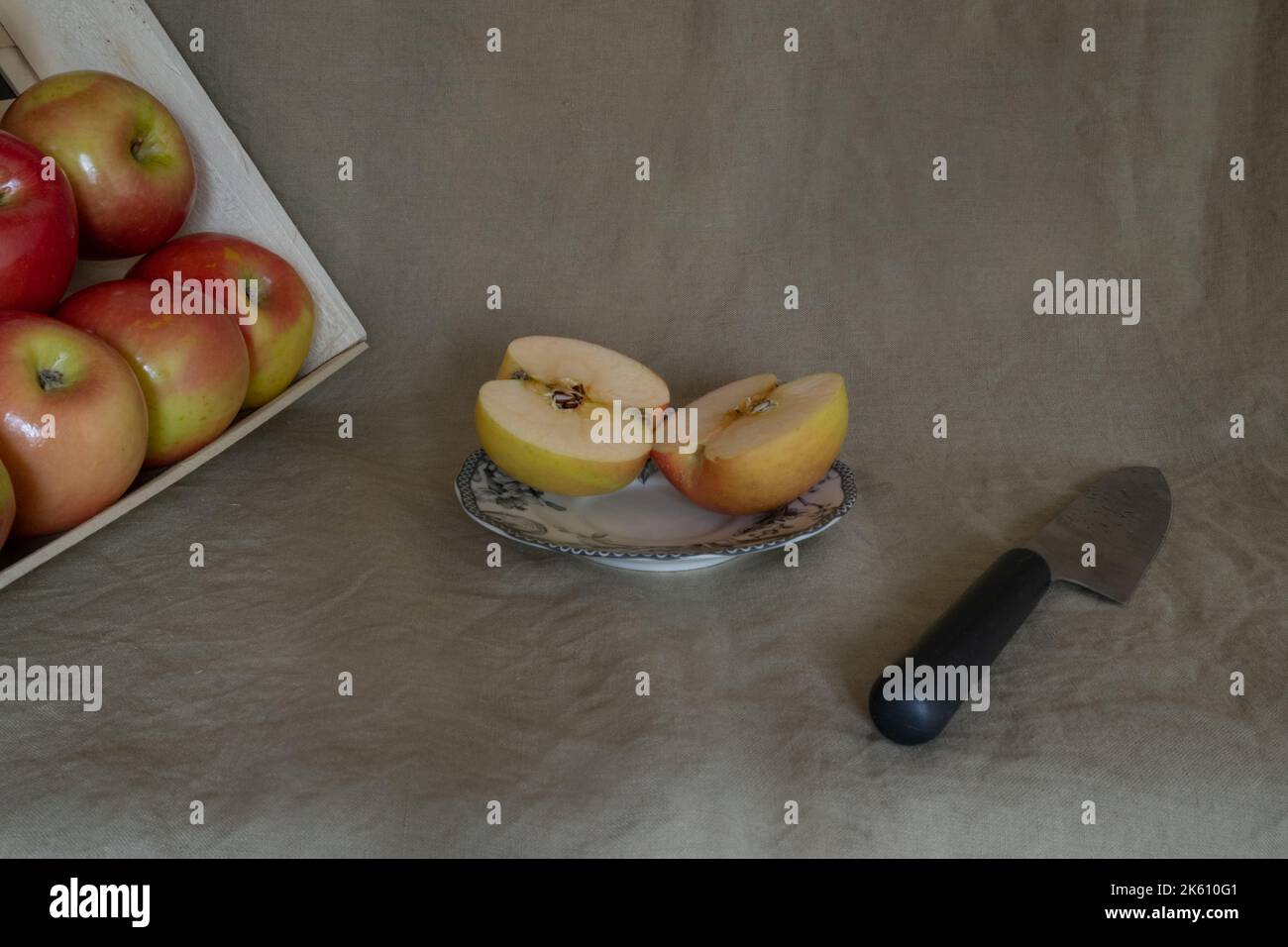 a crate of apples on the left, an apple cut in half in the center, a ...