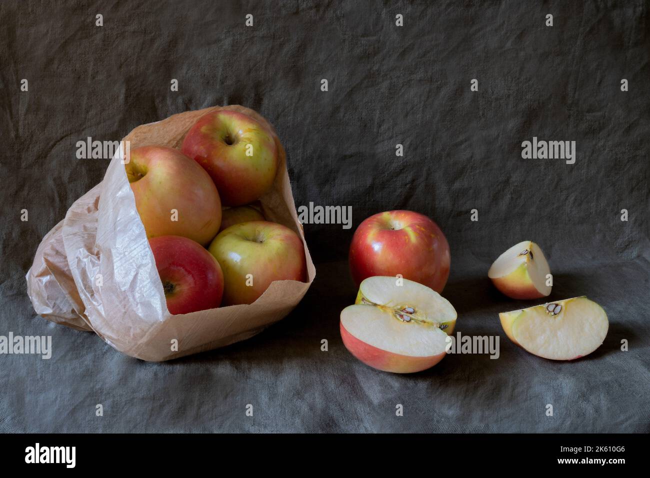 Red apple cut in 3 on a grey linen tablecloth Stock Photo - Alamy