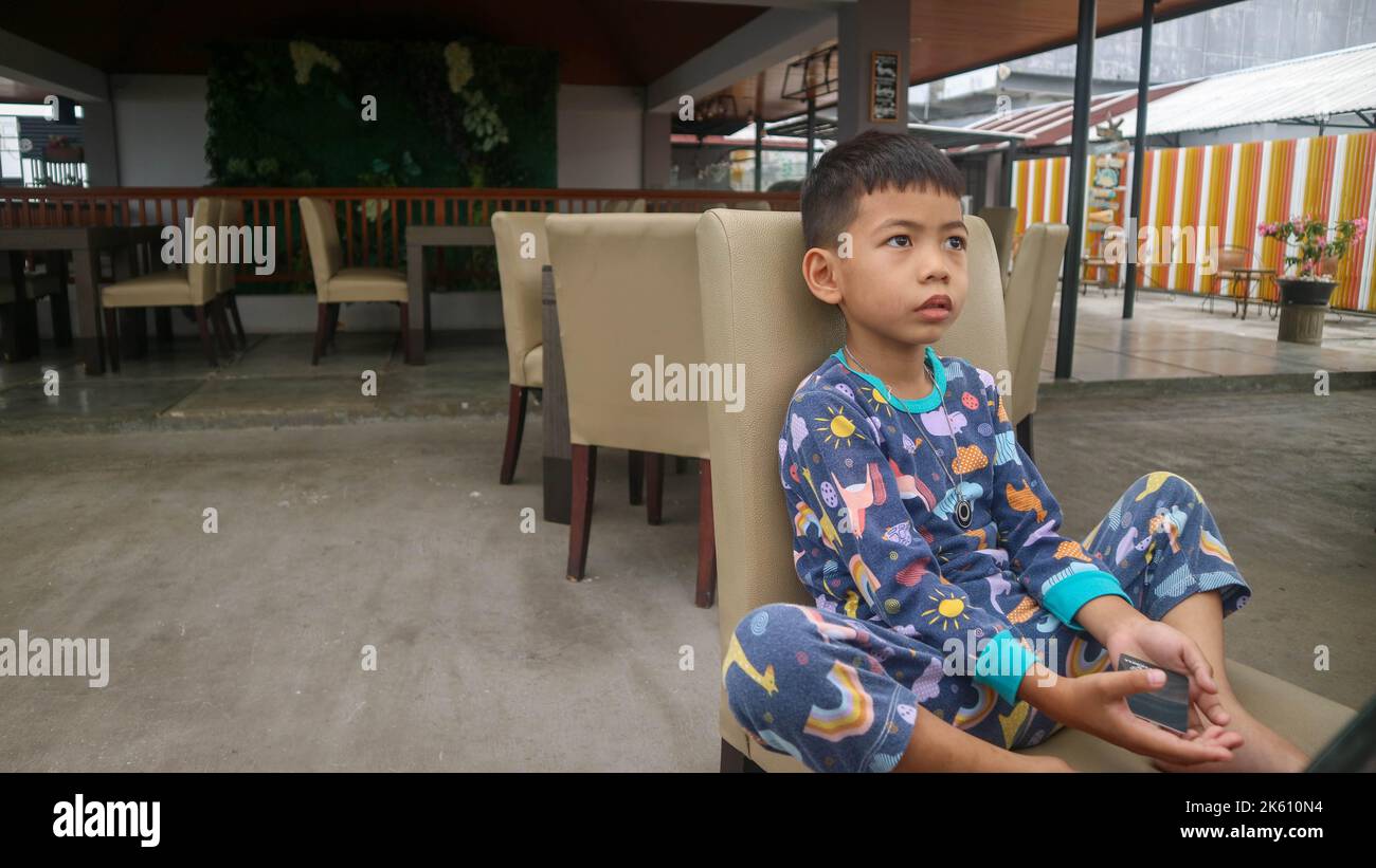 a child is sitting quietly in a chair Stock Photo - Alamy