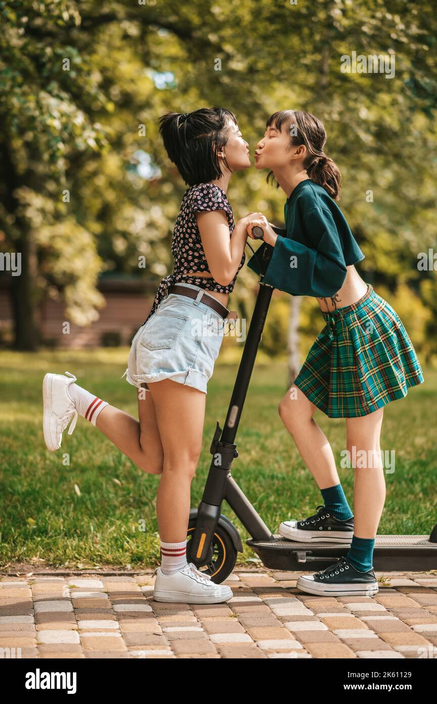 Pretty young girls in the park riding a scooter and enjoying Stock ...