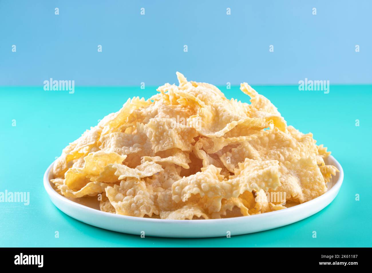 Sfrappole or chiachiere or angel wings on a bright blue background ...