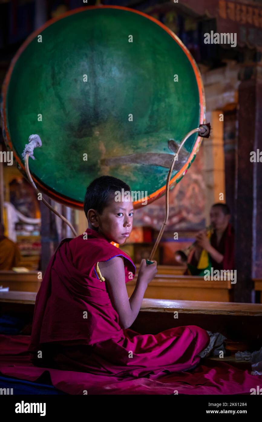 A young monk with a drum at Thikse Monastery (Gompa) during morning ...
