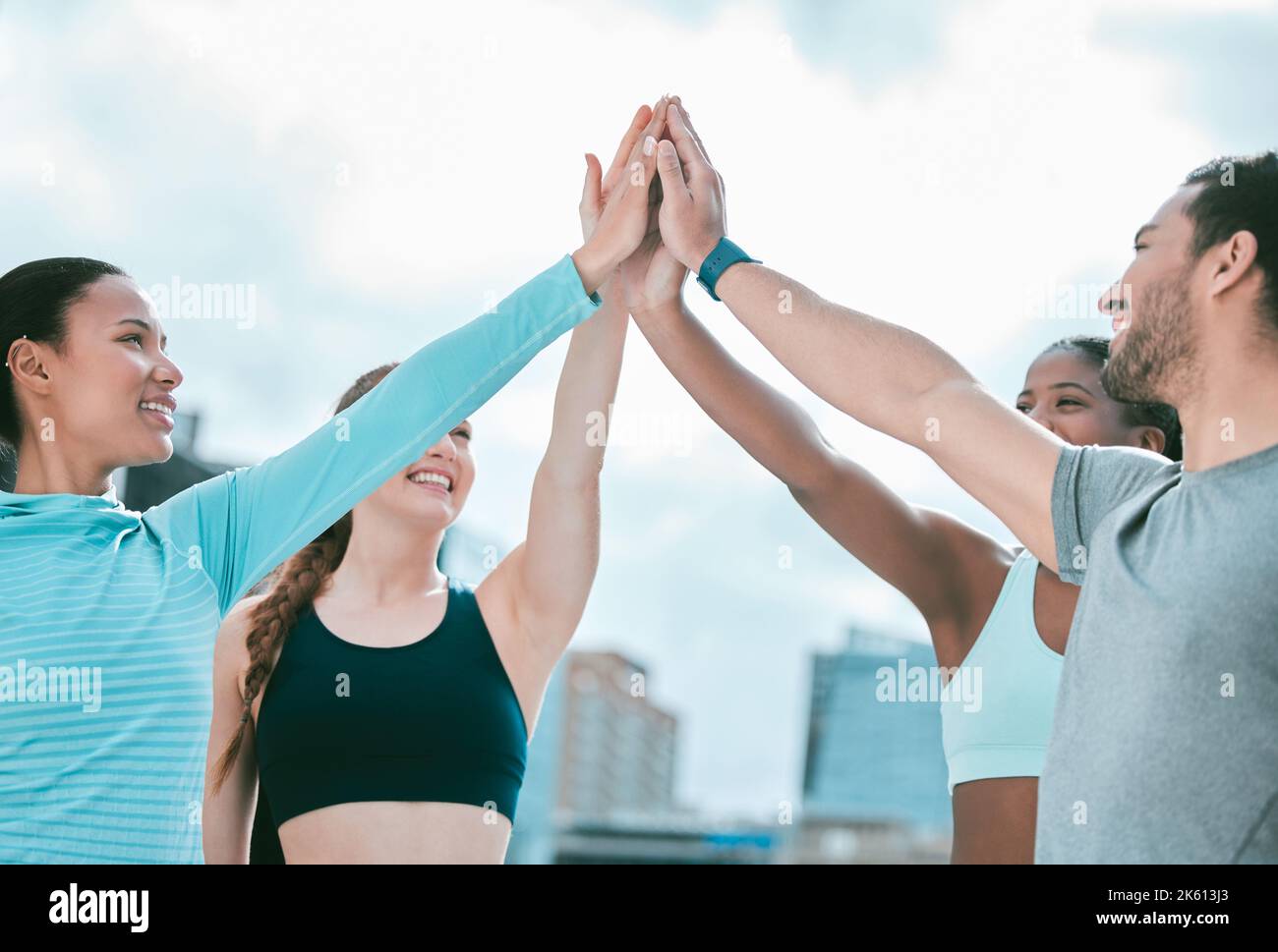 Diverse group of happy sporty people joining hands to high five for ...