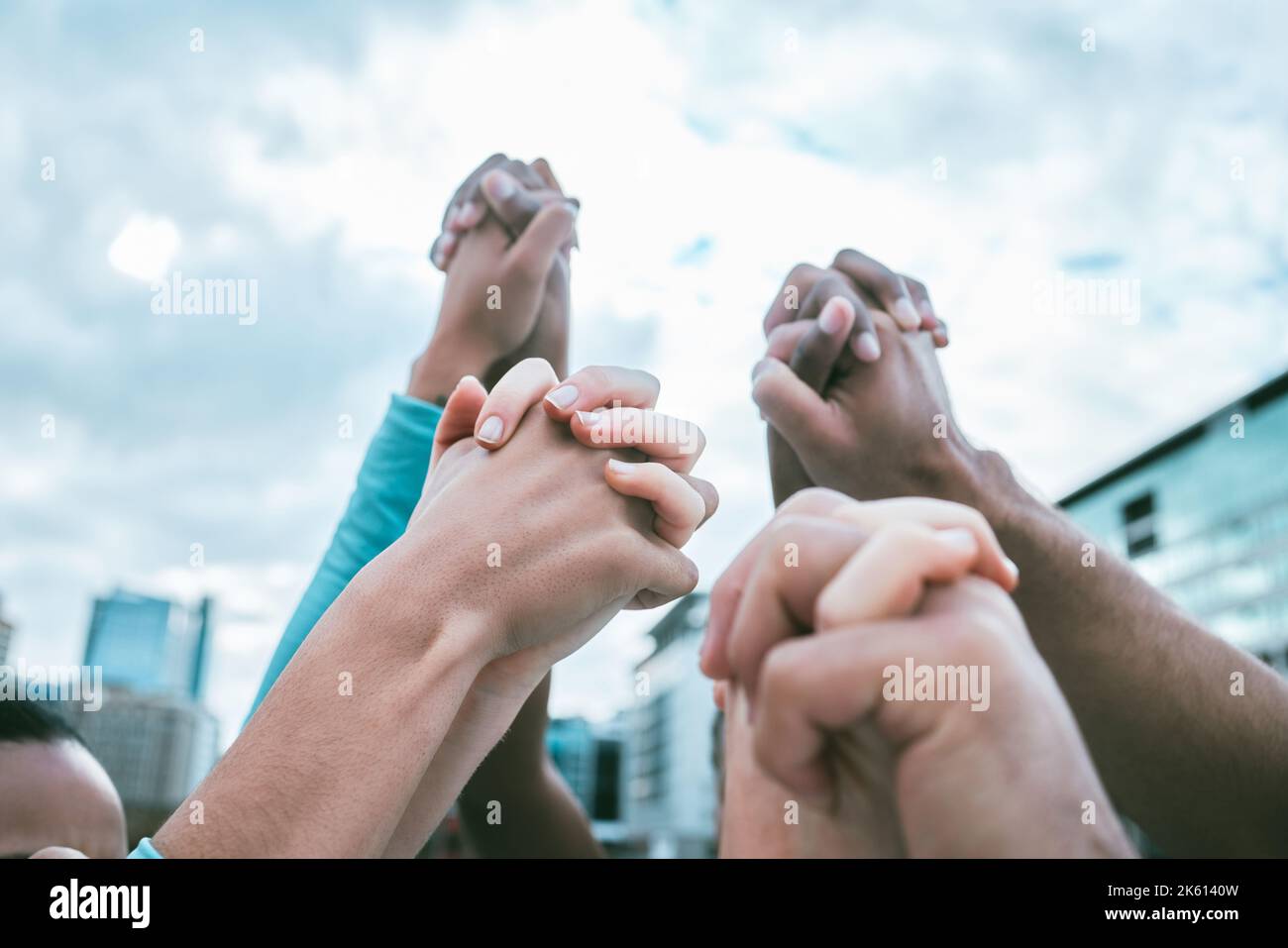 Diverse group of people holding hands with arms raised to express unity ...