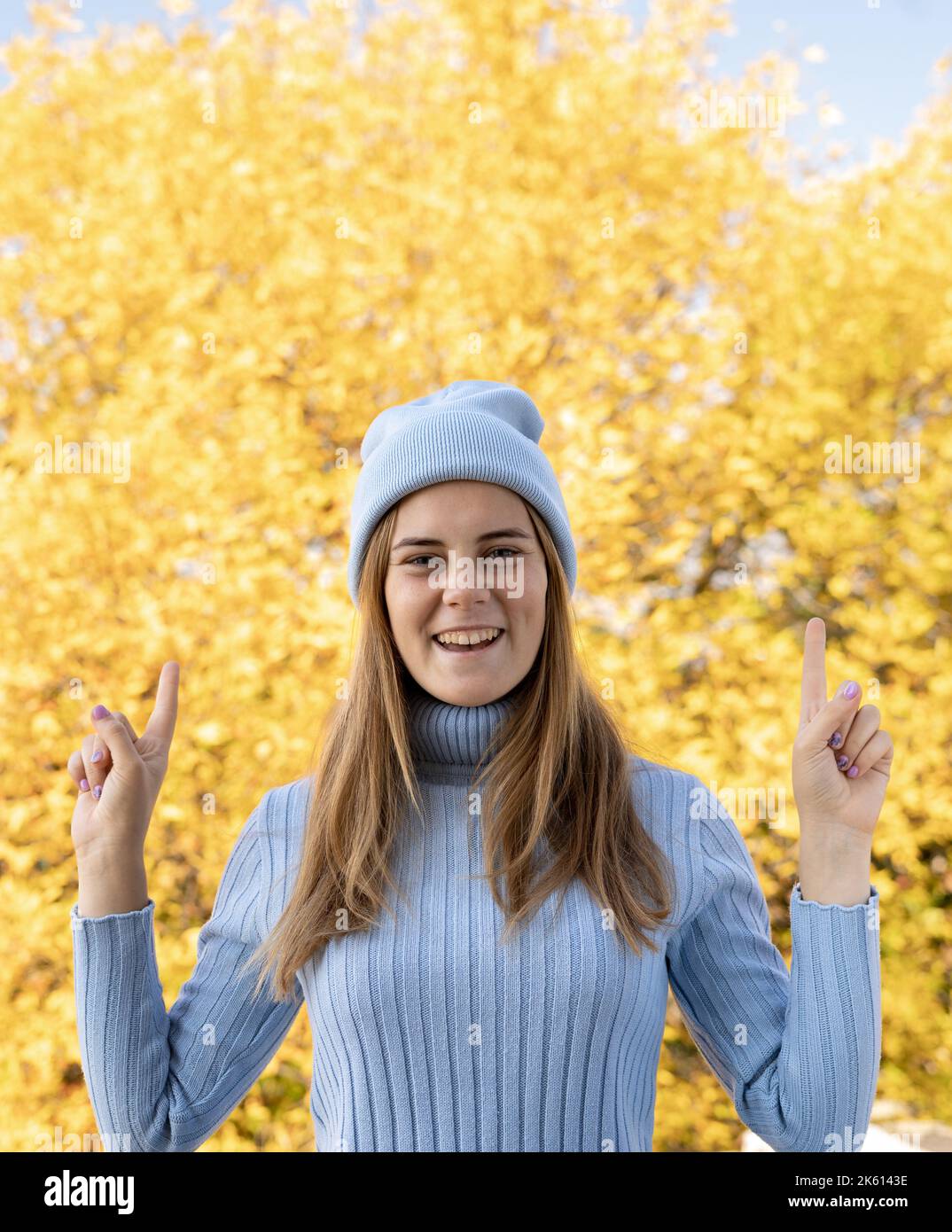 Positive autumn woman in autumn park giving a thumbs up gesture. Warm ...