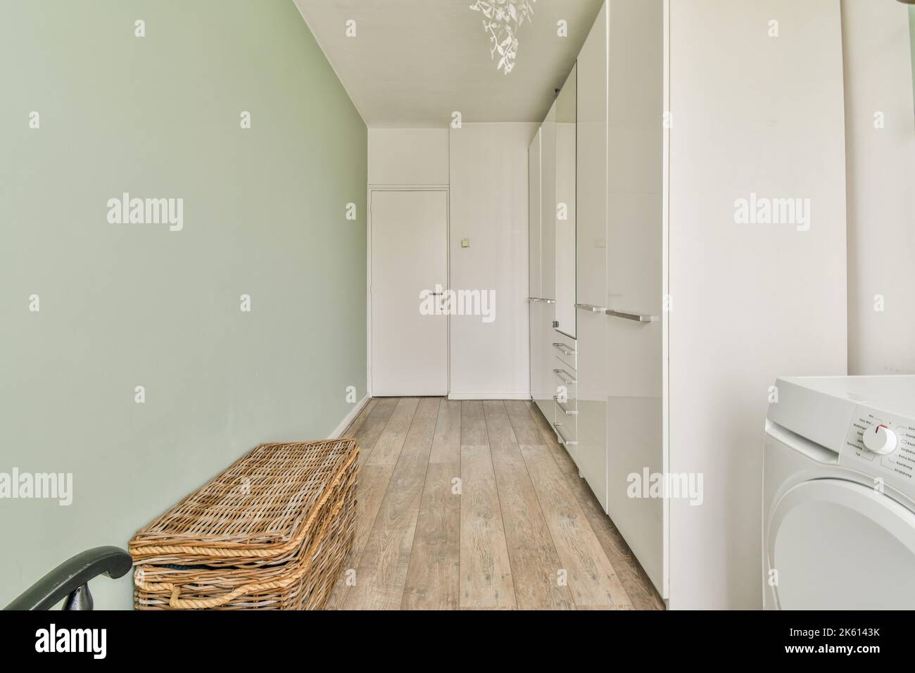 Modern cupboard and wicker basket placed near doors and in spacious ...