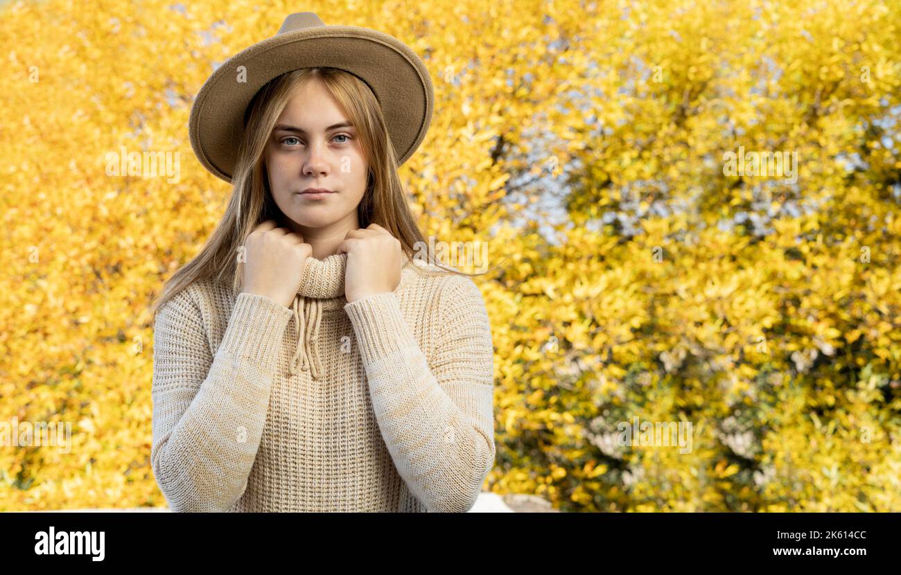 Beautiful young woman in hat standing in a park in autumn. Fall concept ...