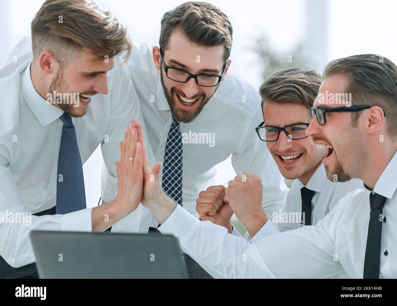 Happy excited team looking at the laptop screen Stock Photo - Alamy