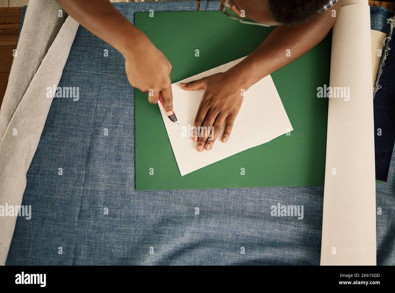 Fashion designer cutting sample with a knife from above. Creative ...
