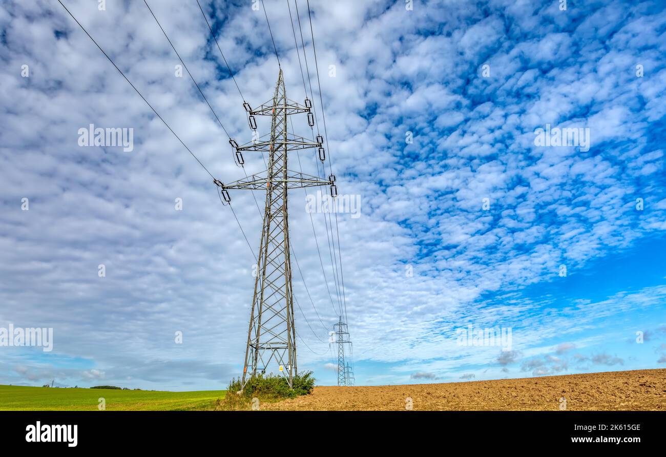 High voltage power lines in field against a blue sky. Autumn fall ...
