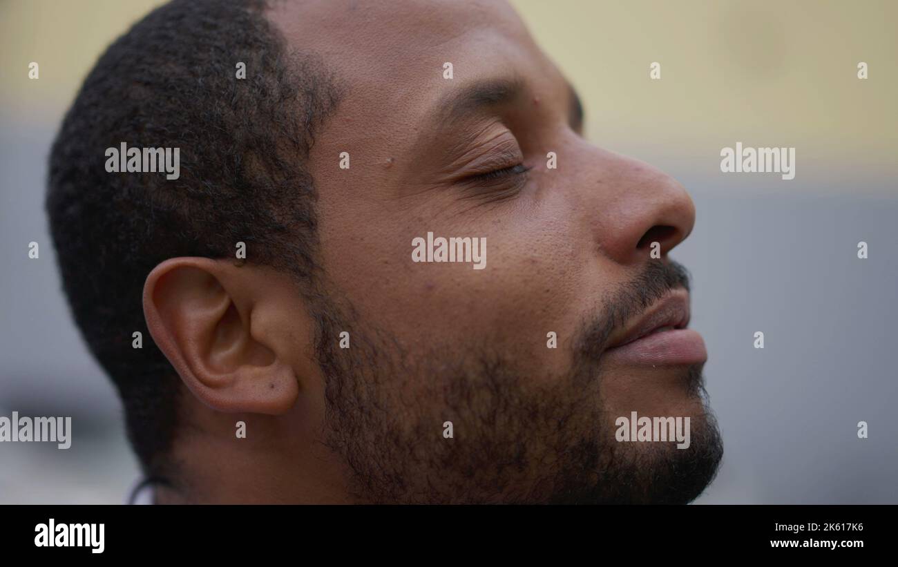 Spiritual young African American man closing eyes in contemplation ...