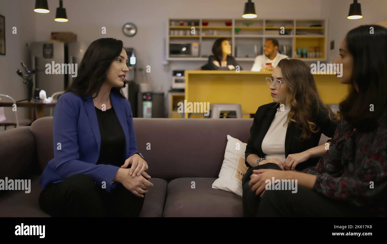 Senior woman executive explaining job to female employees at kitchen resting place at workplace ...