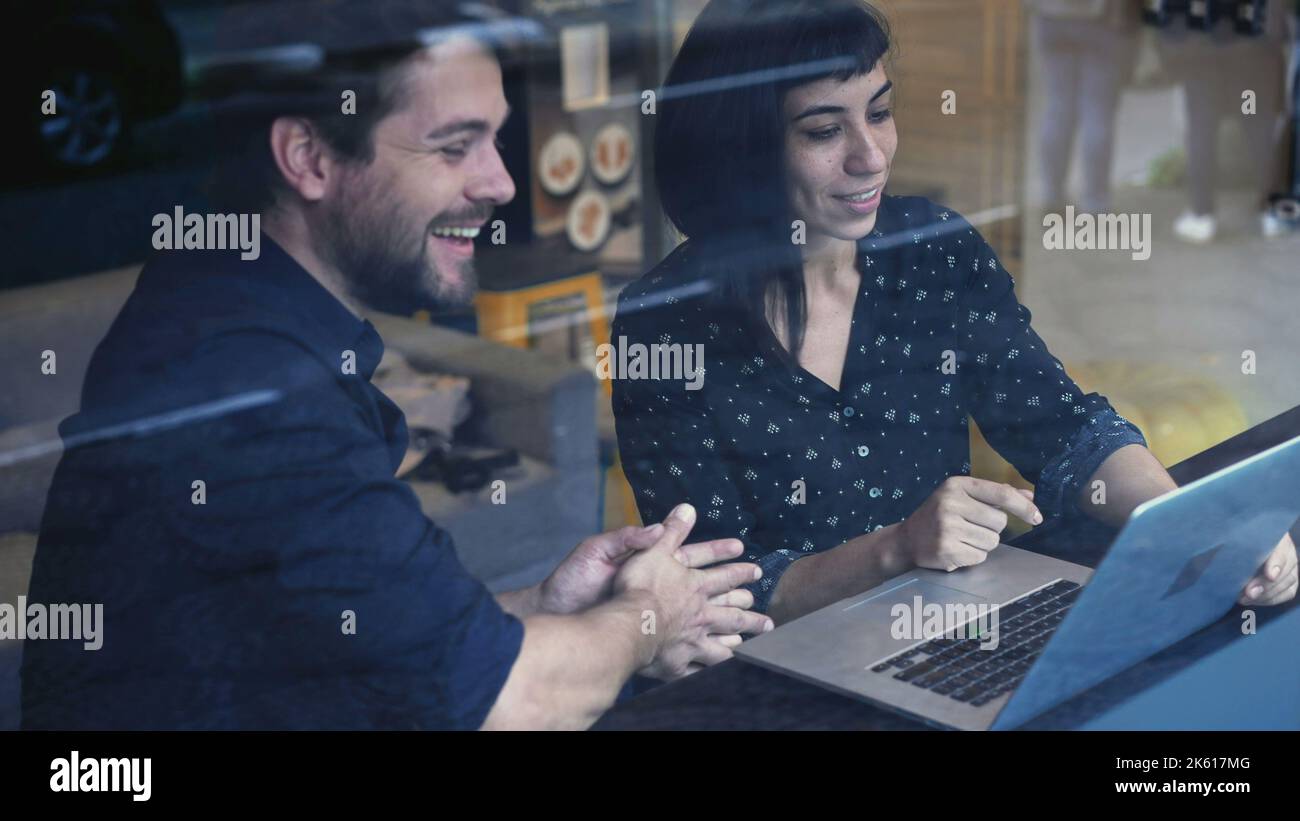 Two colleagues talking about work in front of laptop. Young man ...