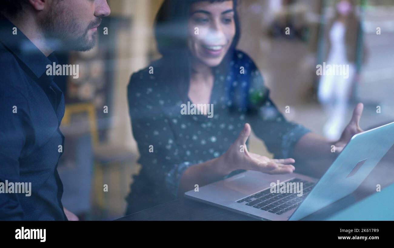 Young hispanic woman explaining work or study to male colleague seen ...