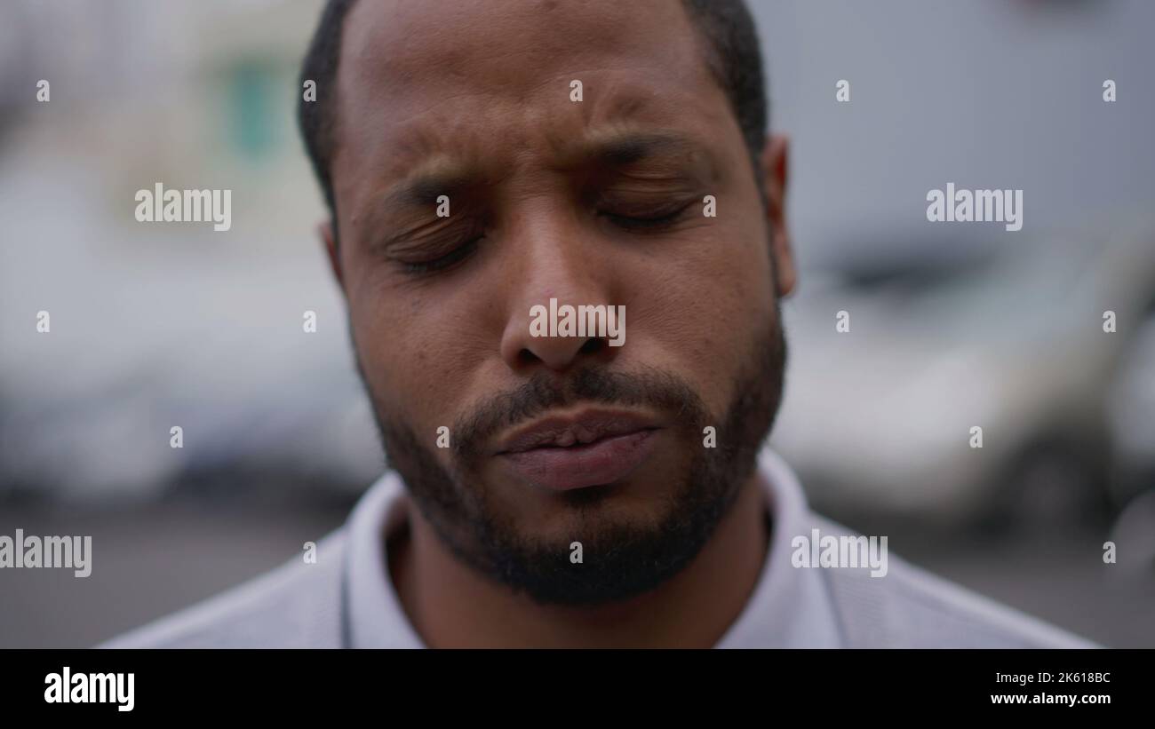 One anxious young African American man in distress closeup face. Portrait of a black person with ...