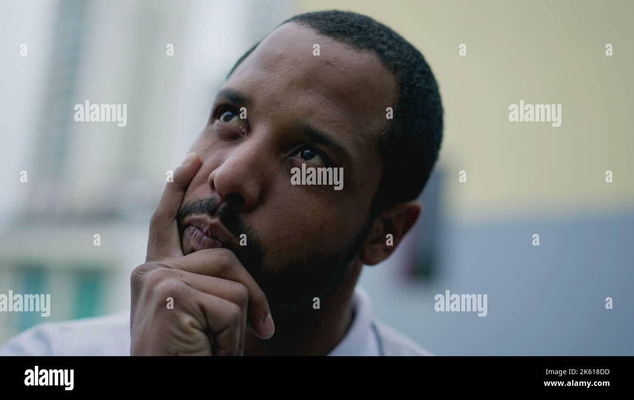 One pensive black man standing outdoors having worried frustration ...