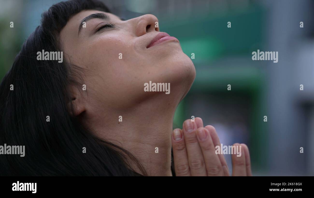 One spiritual young hispanic woman praying to God. Person closing eyes ...
